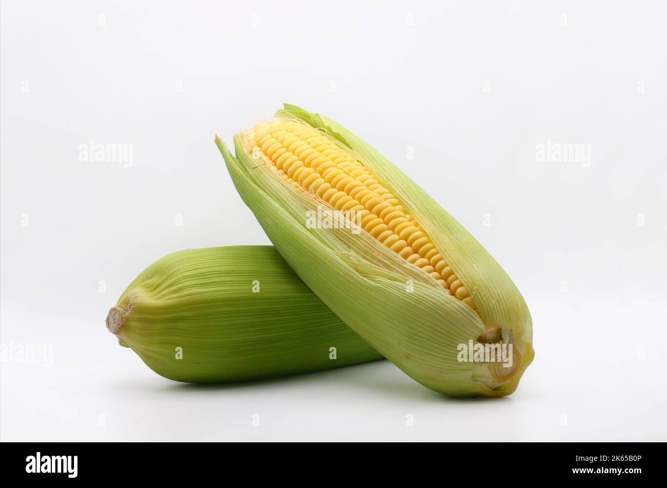Fresh sweet corns with green leaves over white background Stock Photo ...