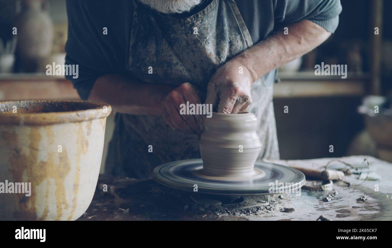 professional male potter creating jar from brown clay in workplace ...