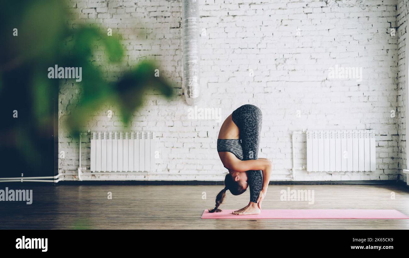 Attractive young girl is doing forward bends, plank, leg split during ...