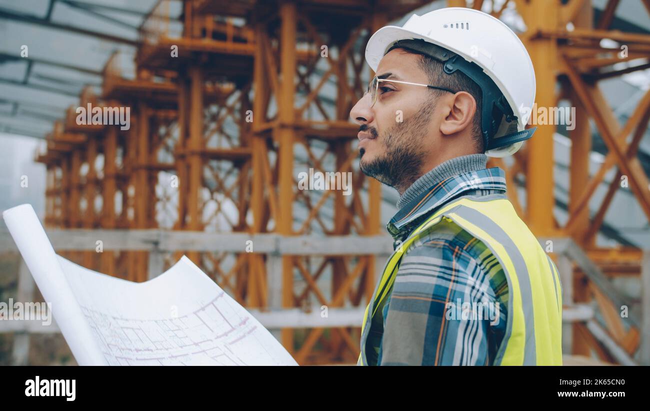 Portrait of engineer planning work at construction site looking at ...