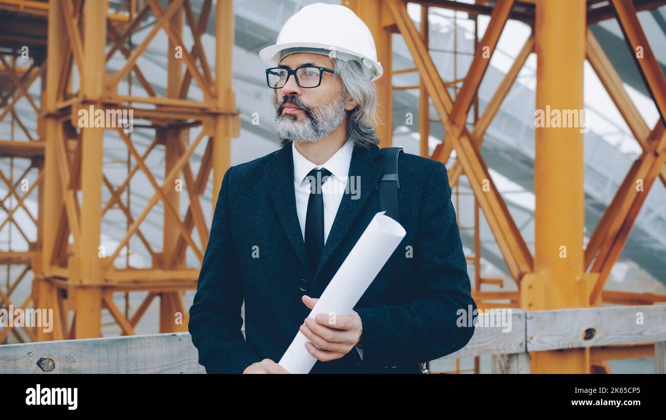 Portrait of serious mature man architect standing in construction site ...
