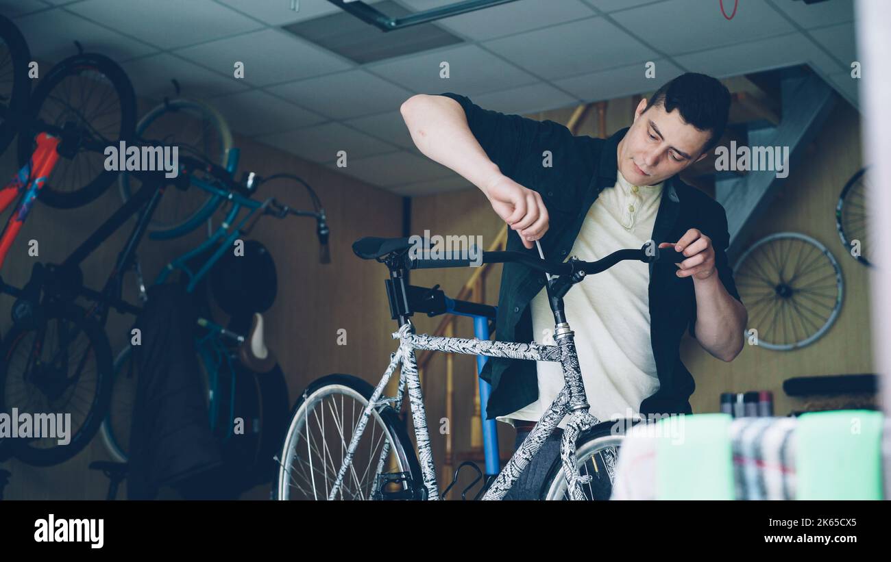 Skilled mechanic is fixing handle-bar of modern bicycle using ...