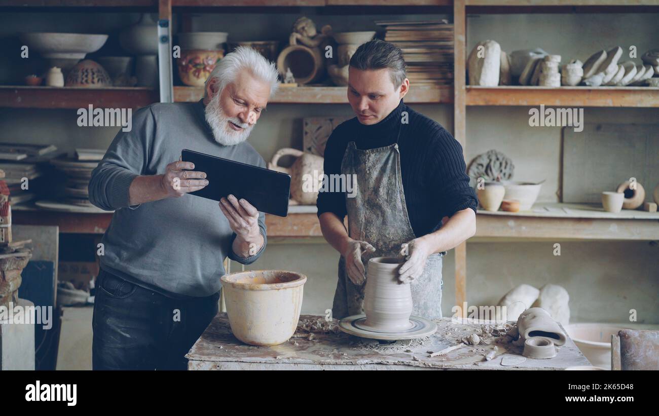 Young male sculptor is making clay figure on throwing wheel while his ...