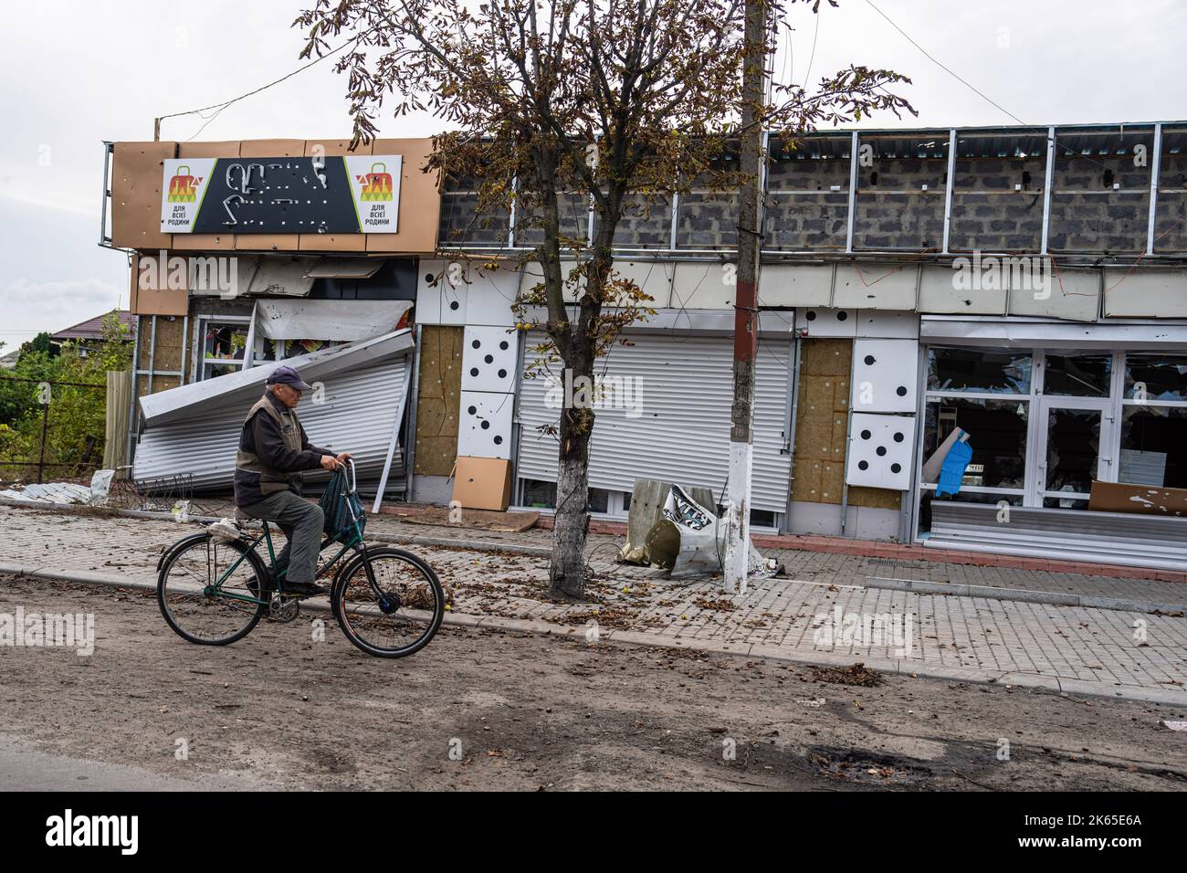 Lyman, Ukraine. 08th Oct, 2022. Civilian rides past damaged buildings ...