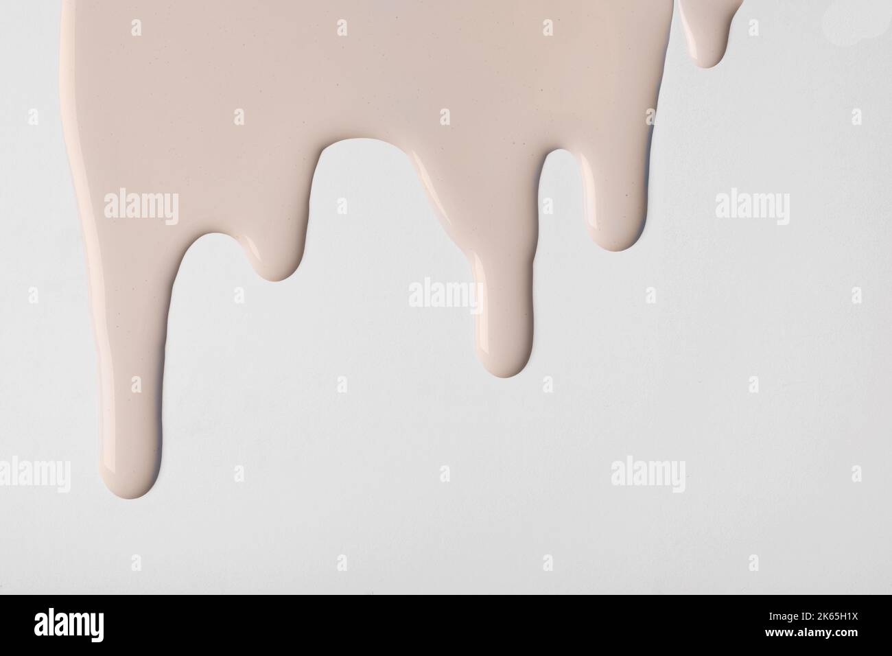 Light brown liquid drops of paint color flow down on isolated white ...