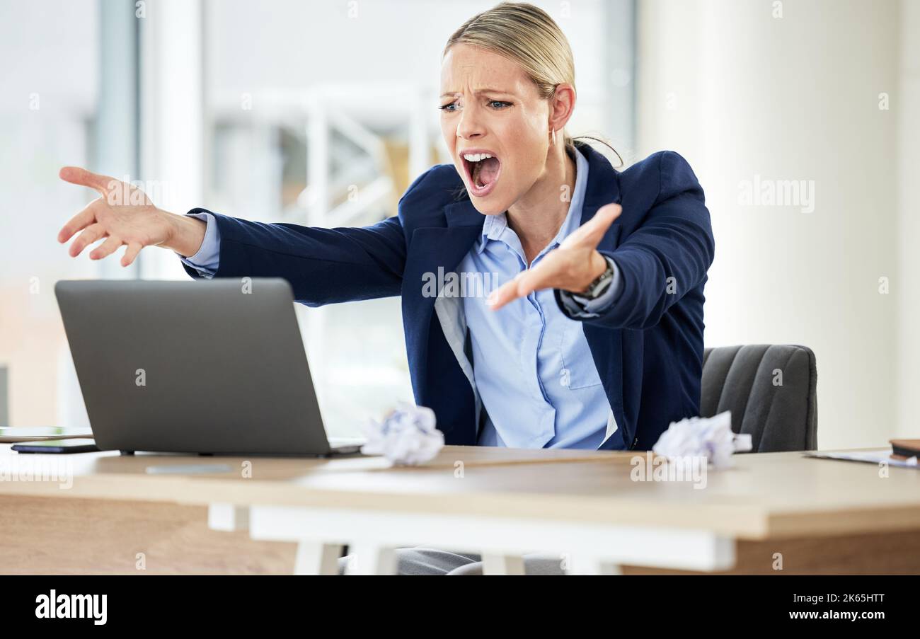 A young caucasian businesswoman yelling while using a laptop in an ...