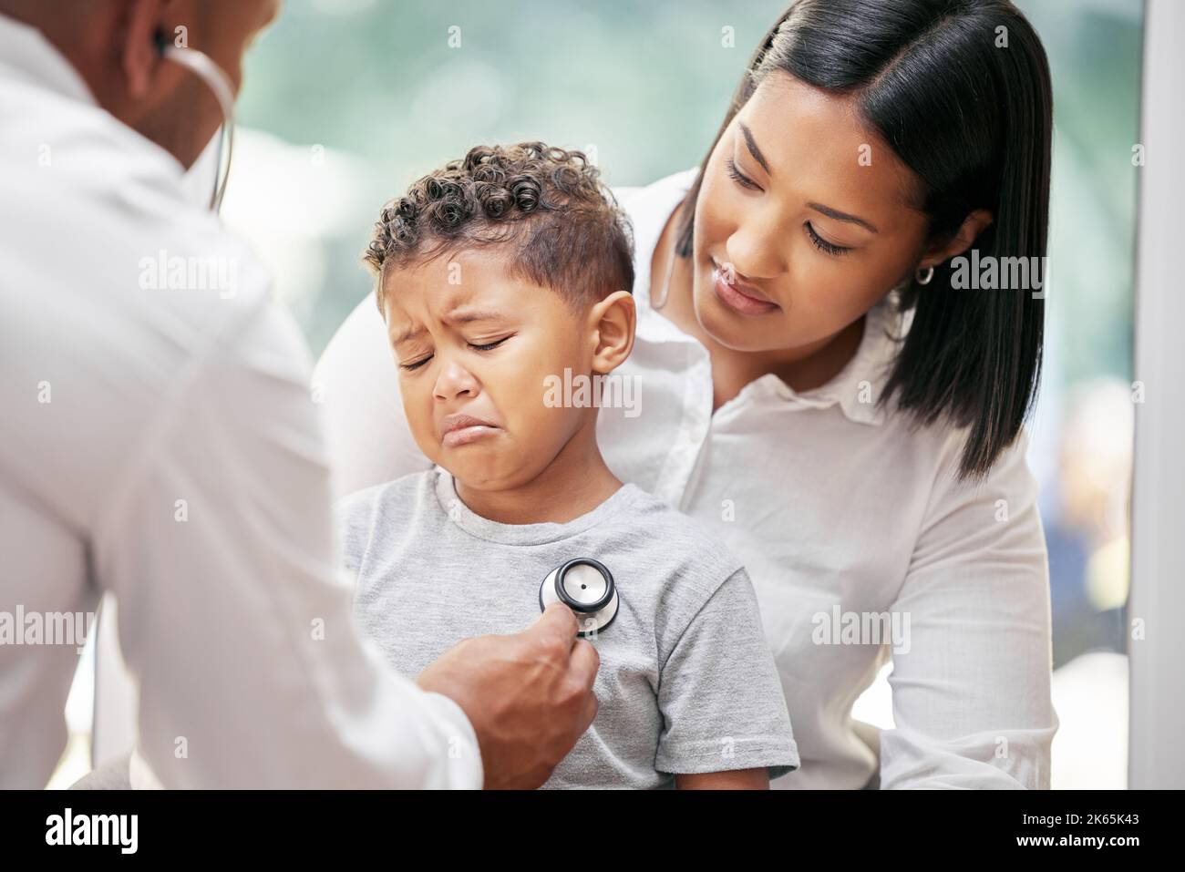Doctor examining sad little boy by stethoscope. Sick boy crying while ...