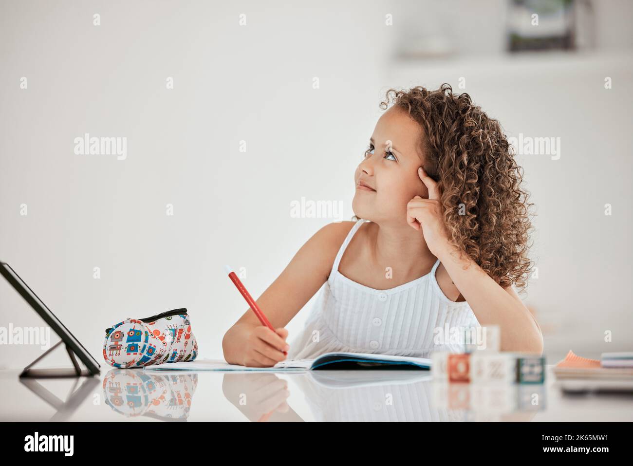Thinking up ideas. a little girl doing homework at home Stock Photo - Alamy