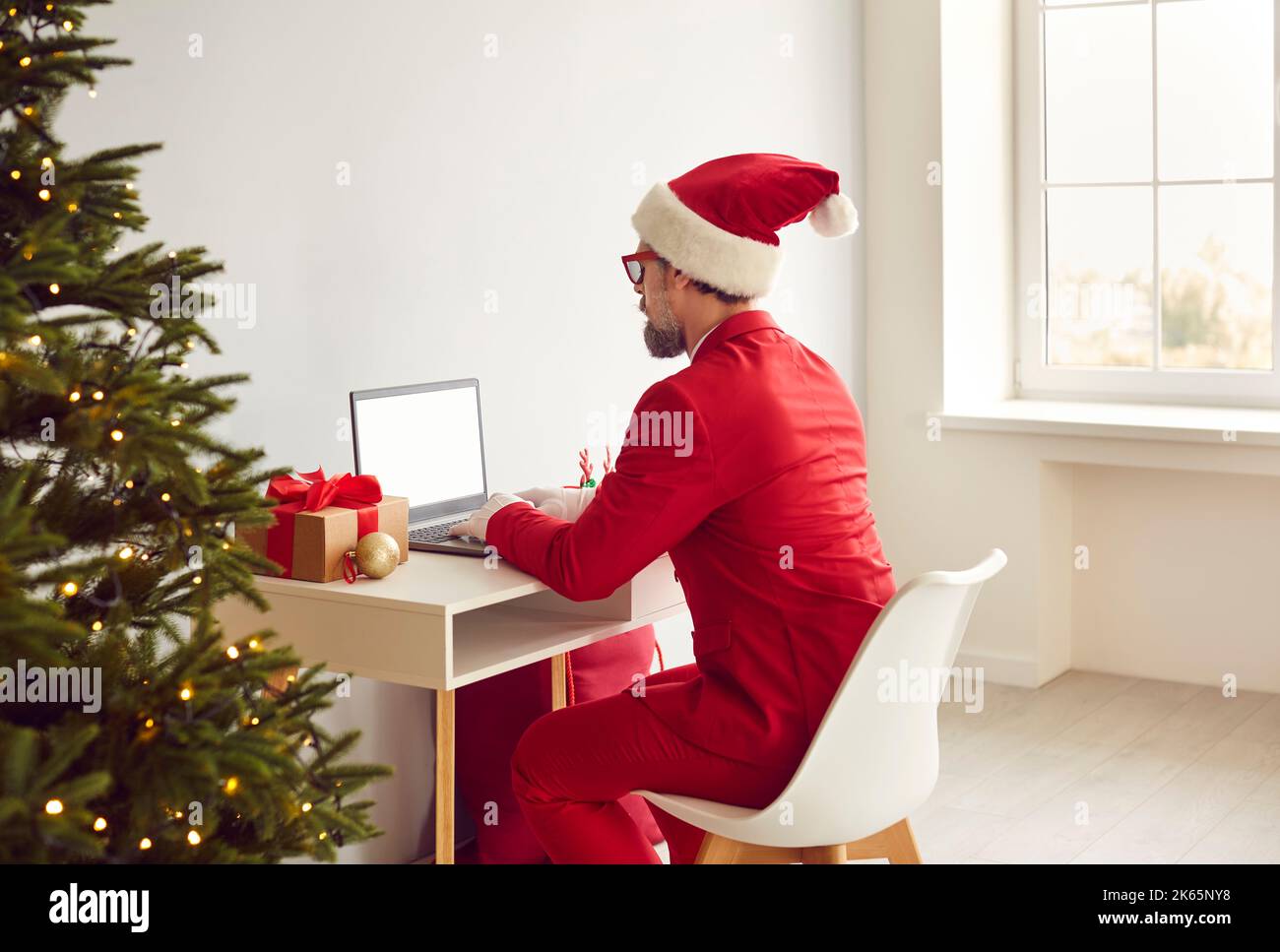 Man in Christmas Santa hat working on laptop while sitting at desk in ...