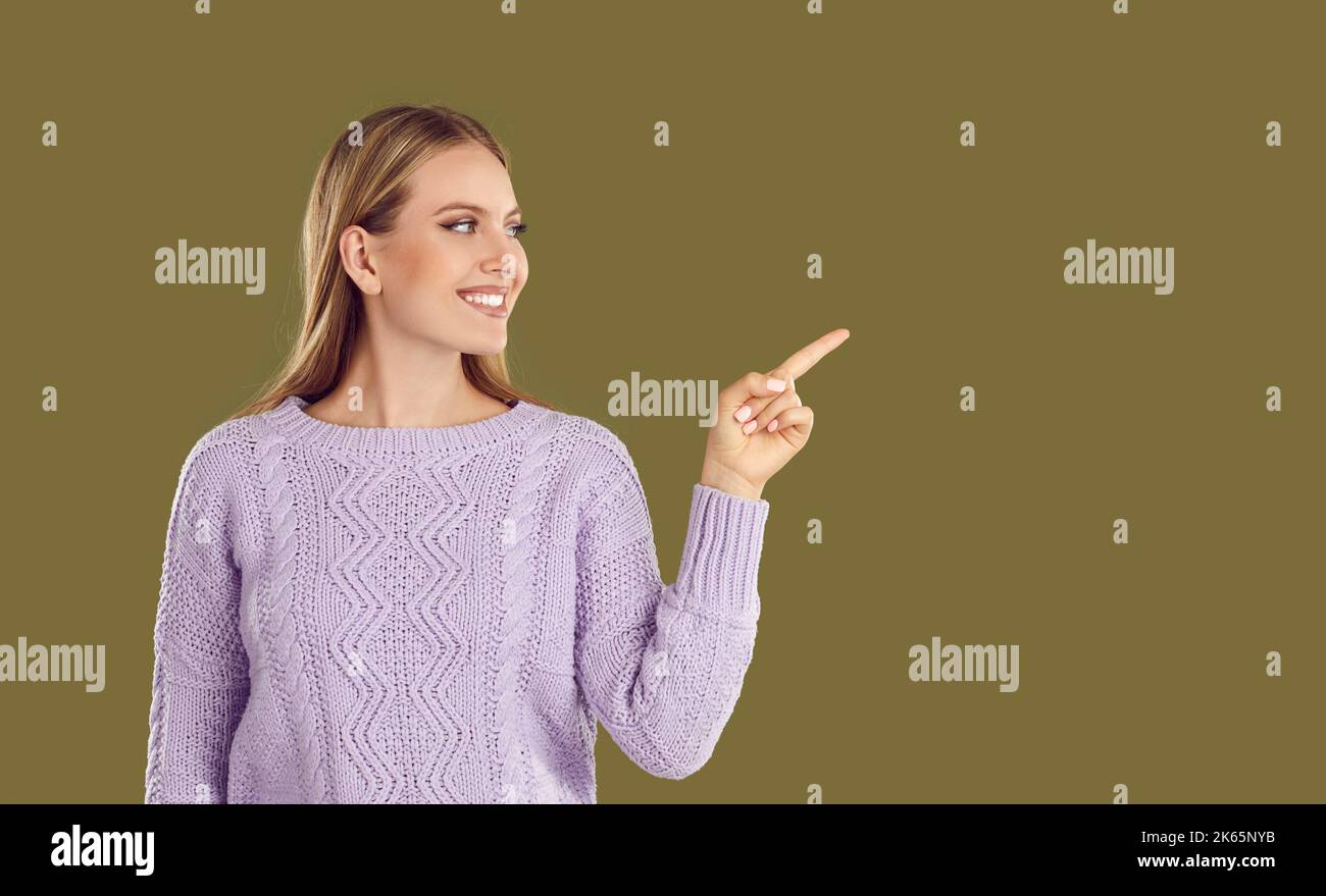 Smiling beautiful woman with index finger pointing sideways on place ...