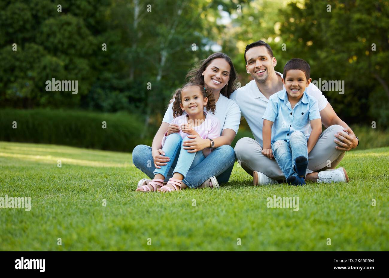 Portrait of carefree mixed race family spending time together at park ...