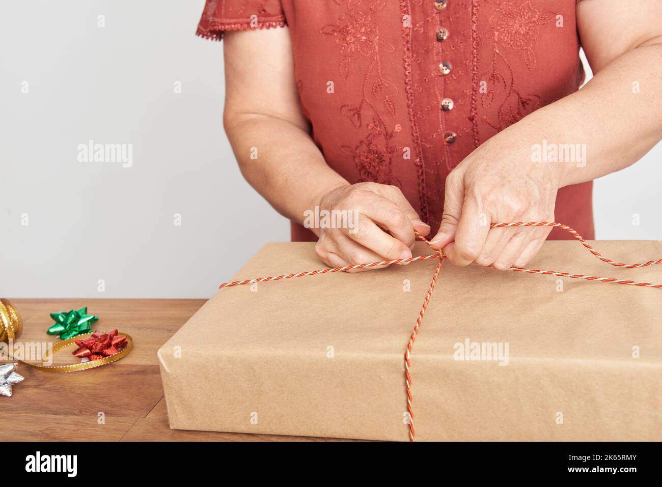Hands of an unknown mature woman tying a Christmas gift with a ...