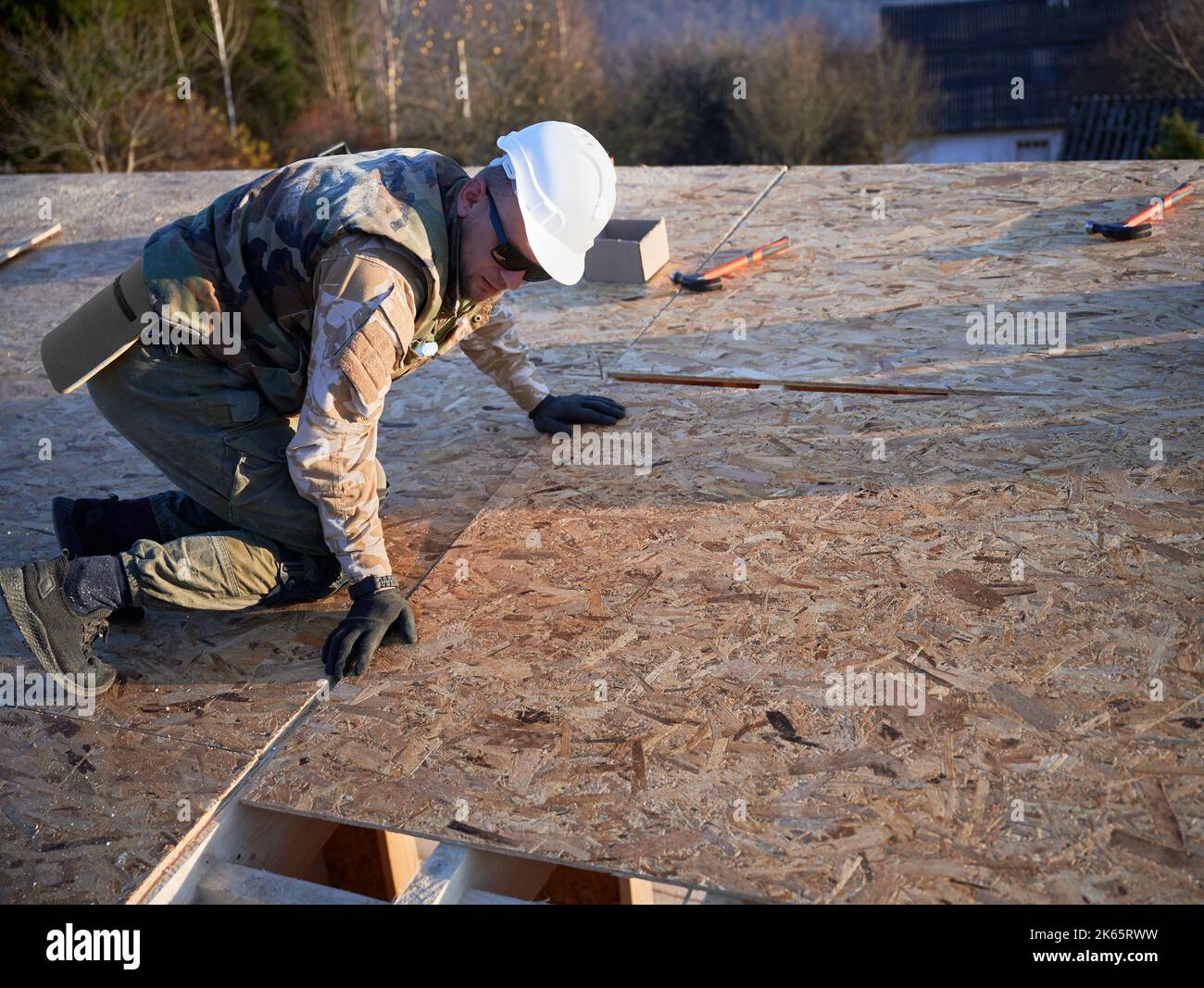 Carpenter mounting wooden OSB board on rooftop of future cottage. Man ...