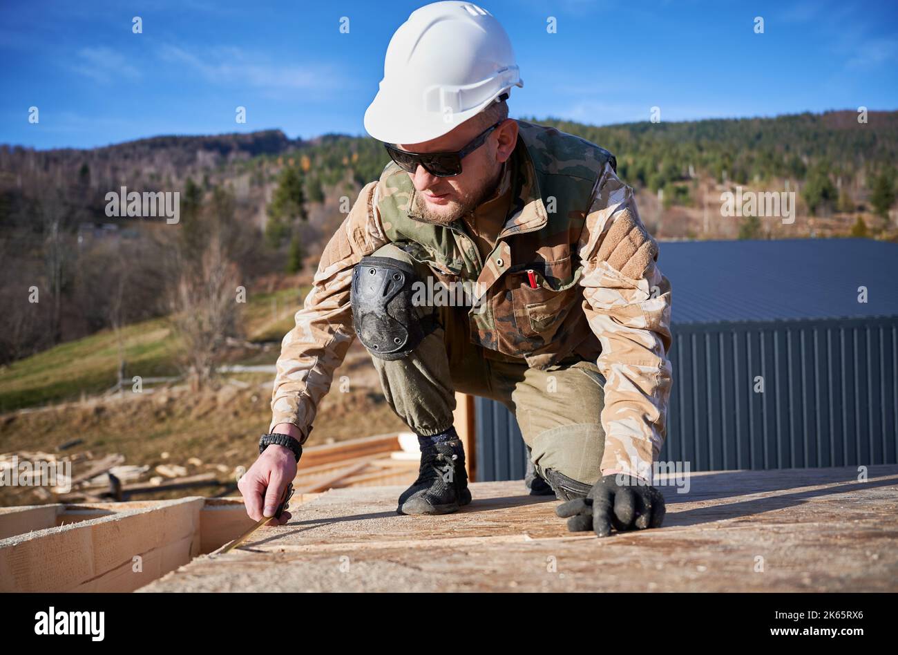 Man worker building wooden frame house. Carpenter using tape measure ...