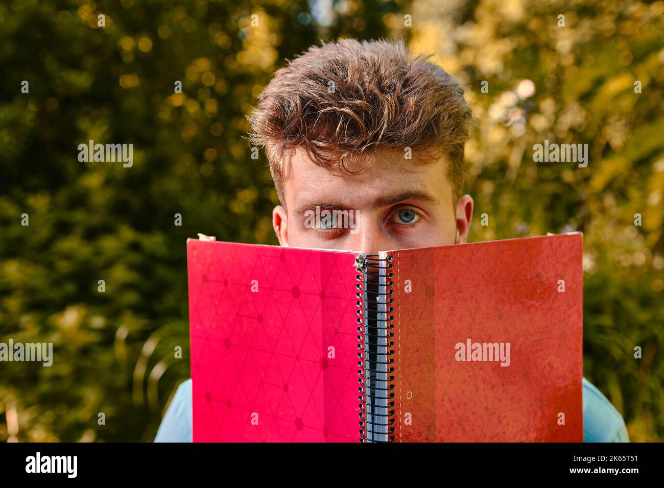 A blue-eyed student looking into the camera and covering part of his ...