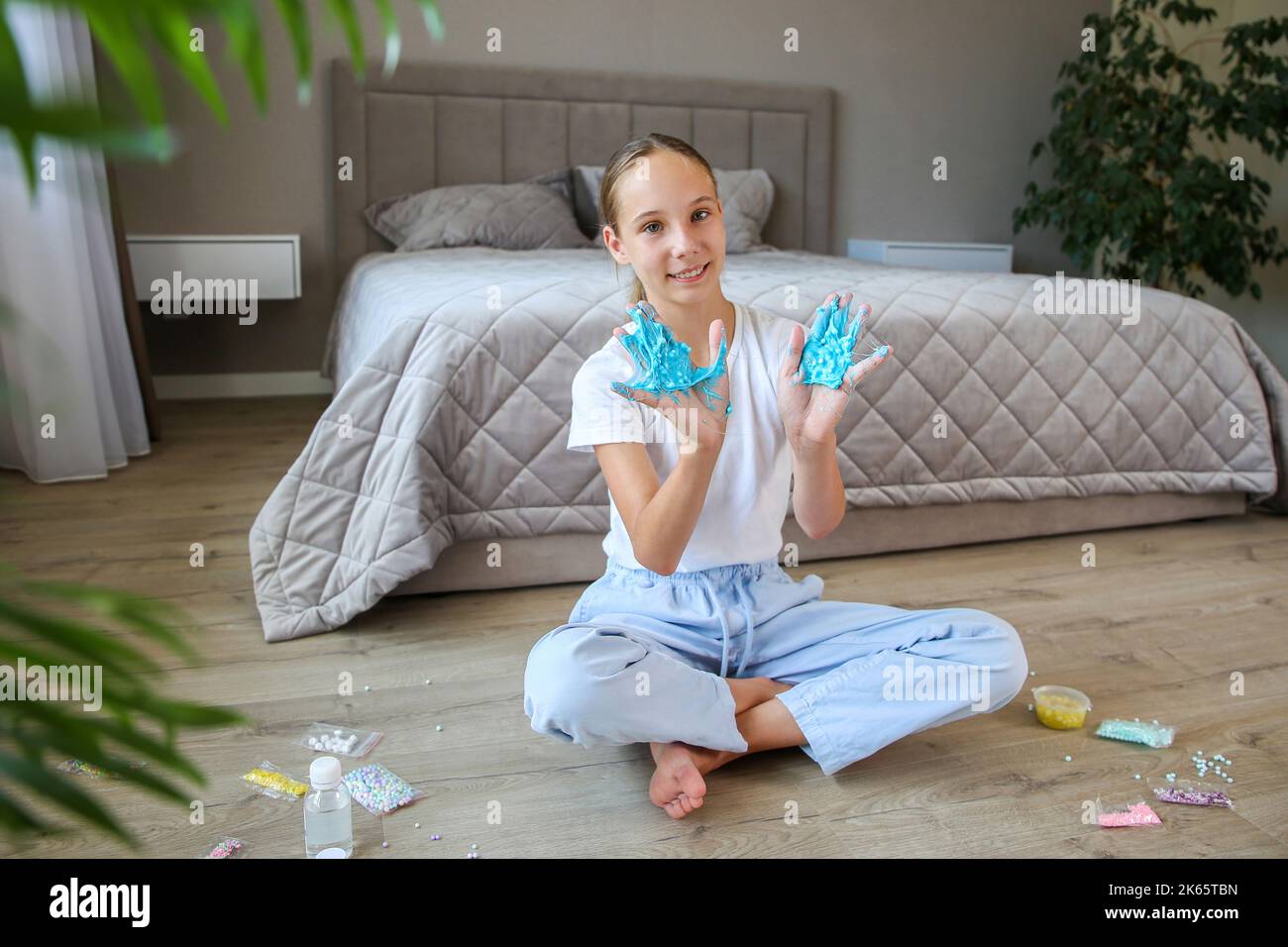 A teenager is playing with a blue slime. Concept of girl made homemade ...