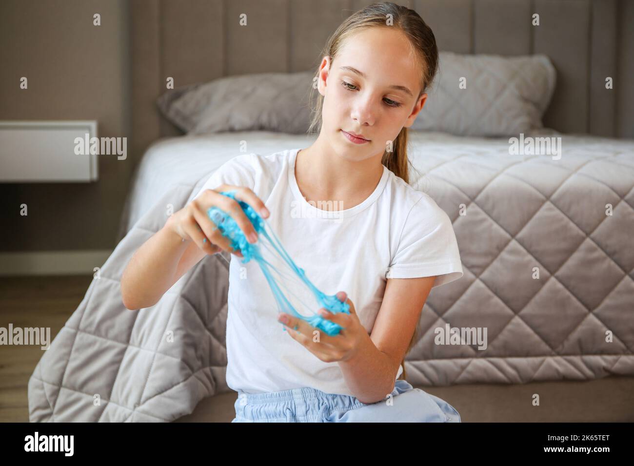 A teenager is playing with a blue slime. Concept of girl made homemade ...