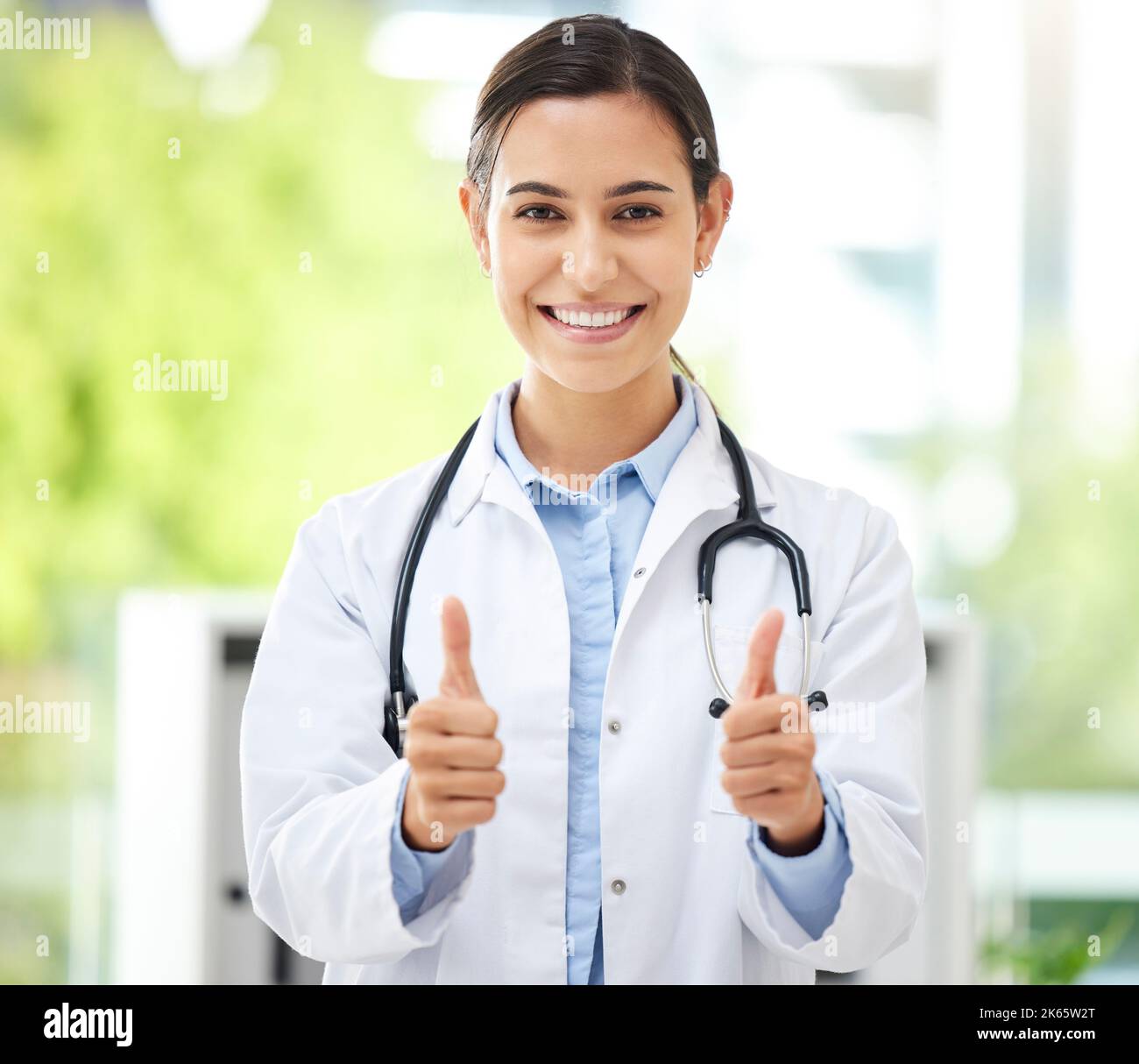 Portrait of a young mixed race doctor making a thumbs up gesture while ...