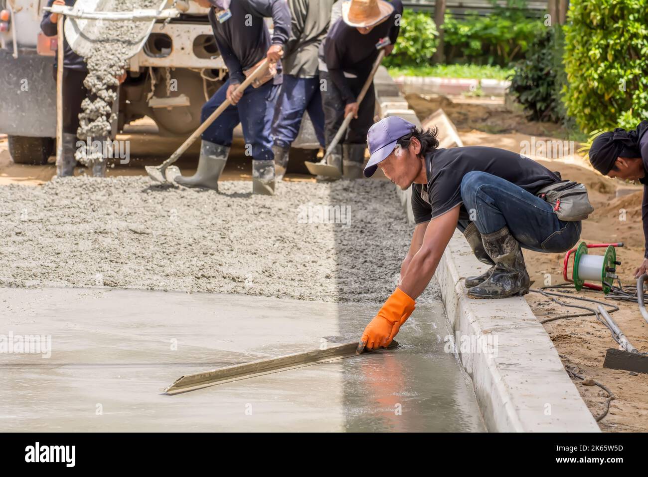 Construction worker pouring cement for doing the road Stock Photo - Alamy