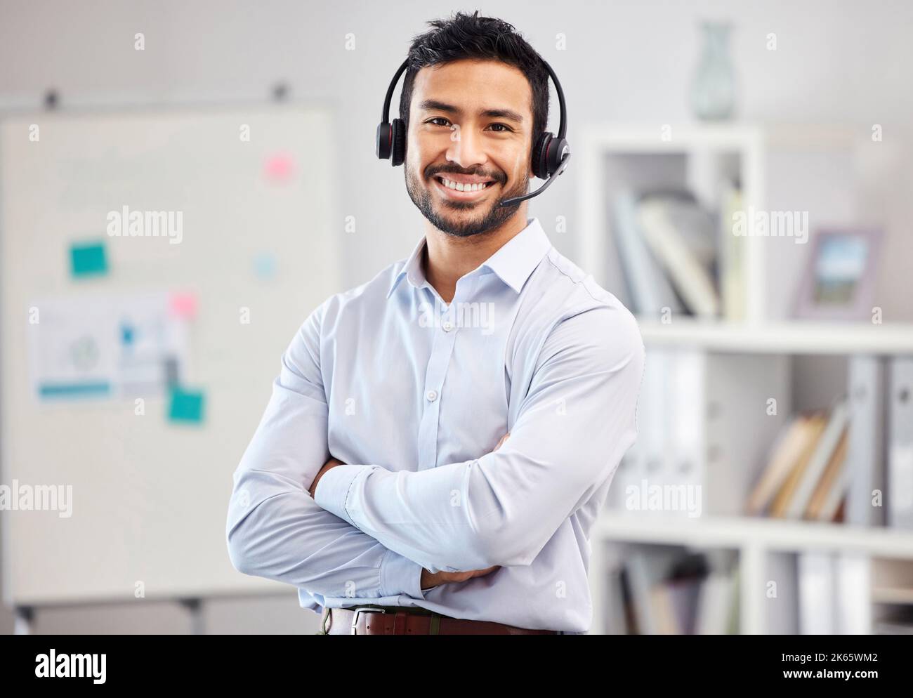 Young happy mixed race call center agent standing with his arms crossed ...