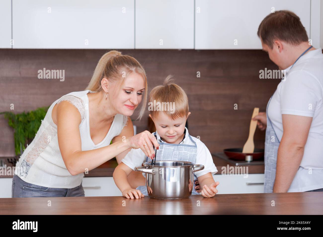 Kind caucasian parents teaching their little adorable son how to cook ...