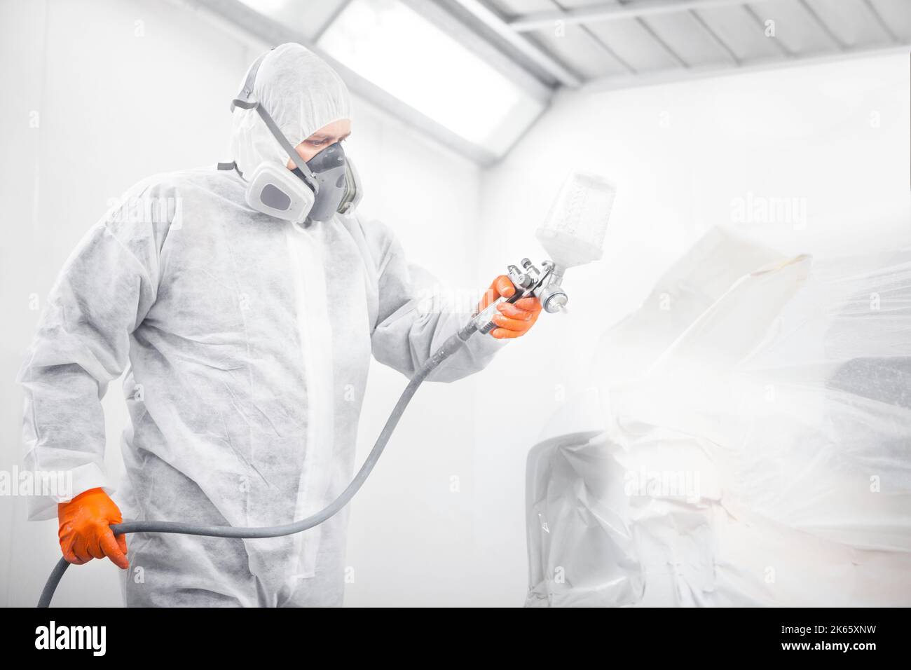 Worker spraying white paint with spray gun on car Stock Photo - Alamy