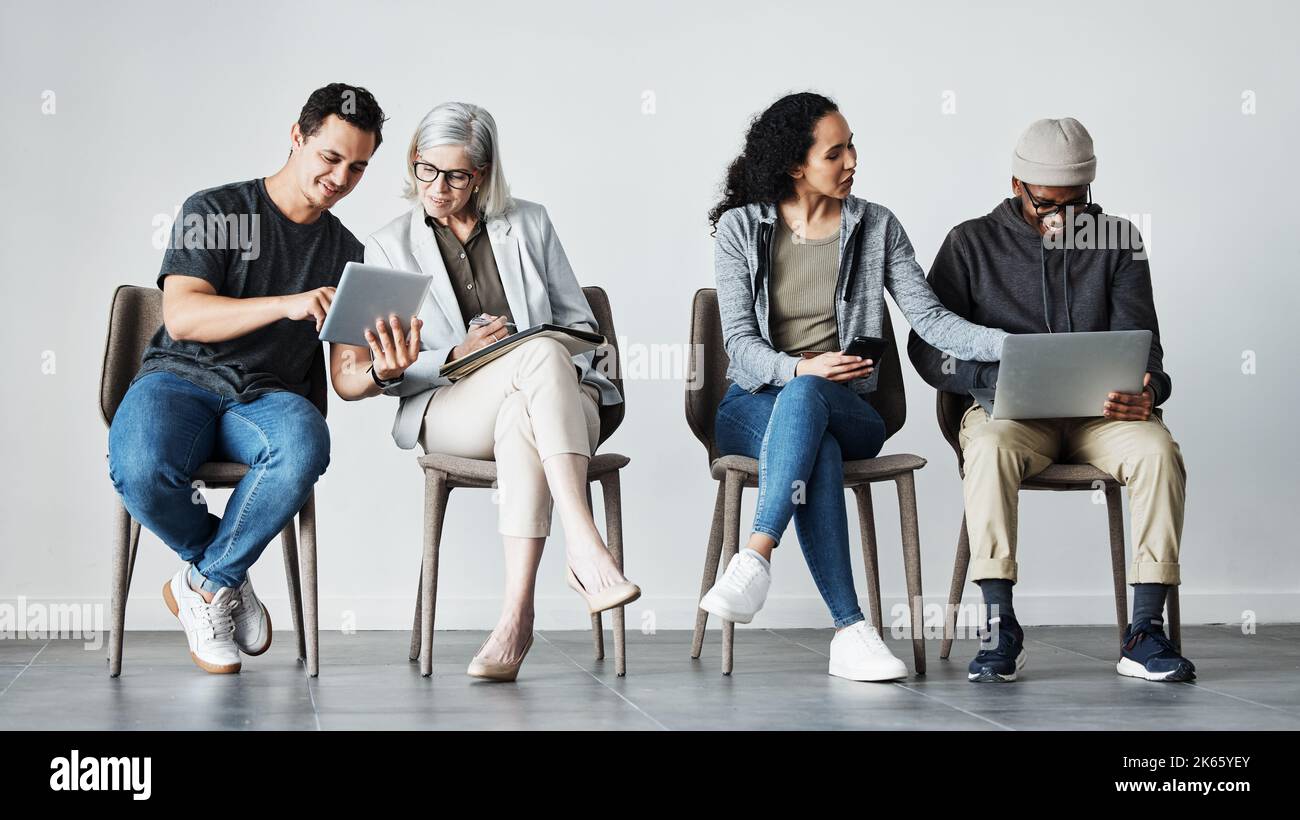 Businesspeople sitting in row using tech devices. Diverse ...