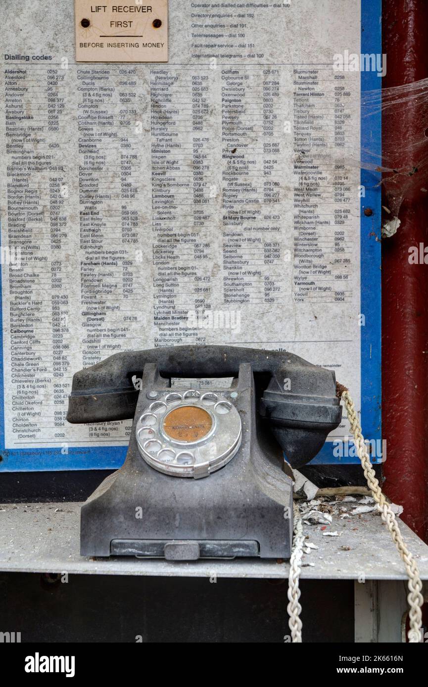 Black vintage old fashioned telephone with dial in red telephone box ...