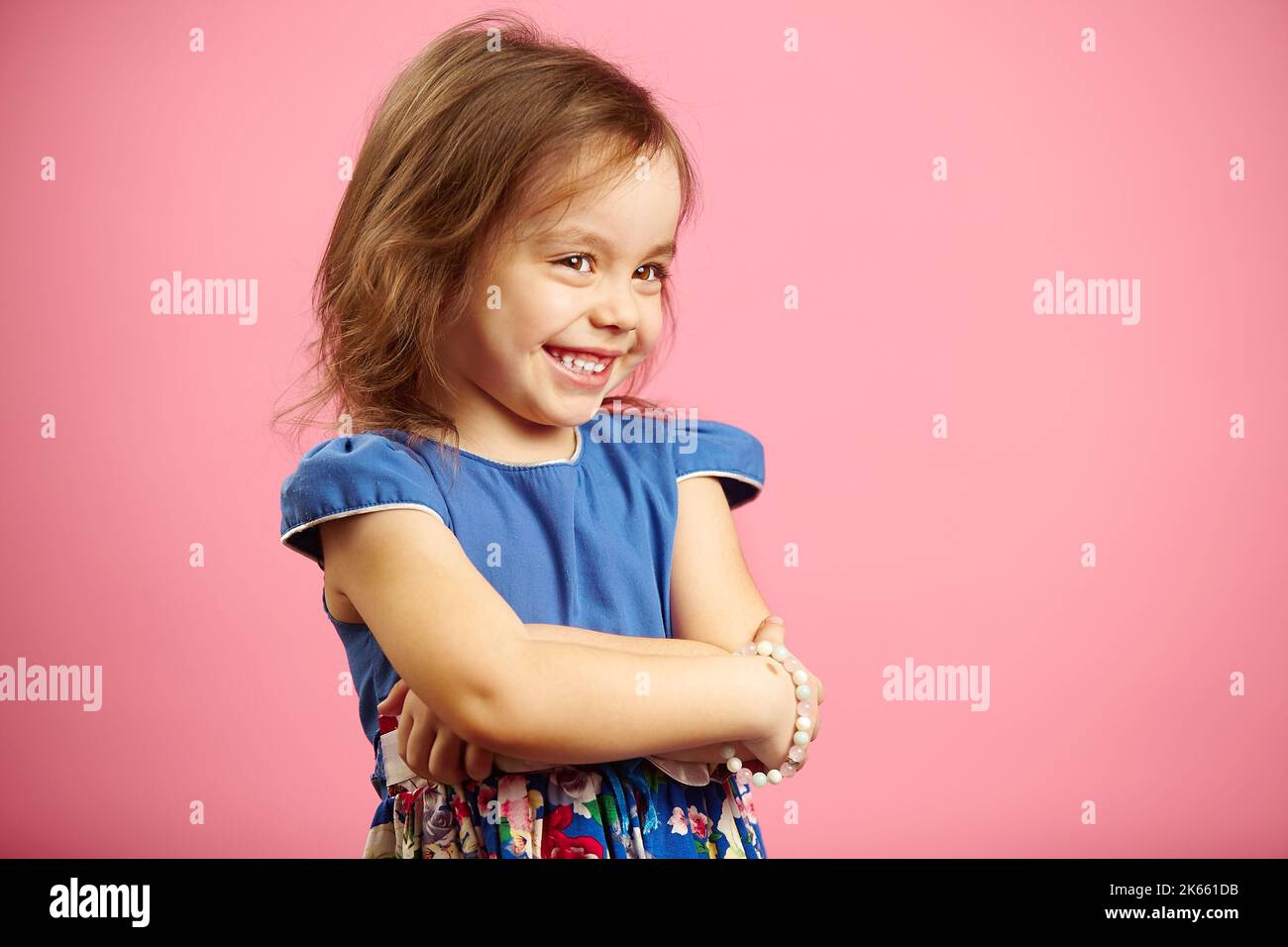 Children's beautiful girl with shyness stands on pink isolated ...