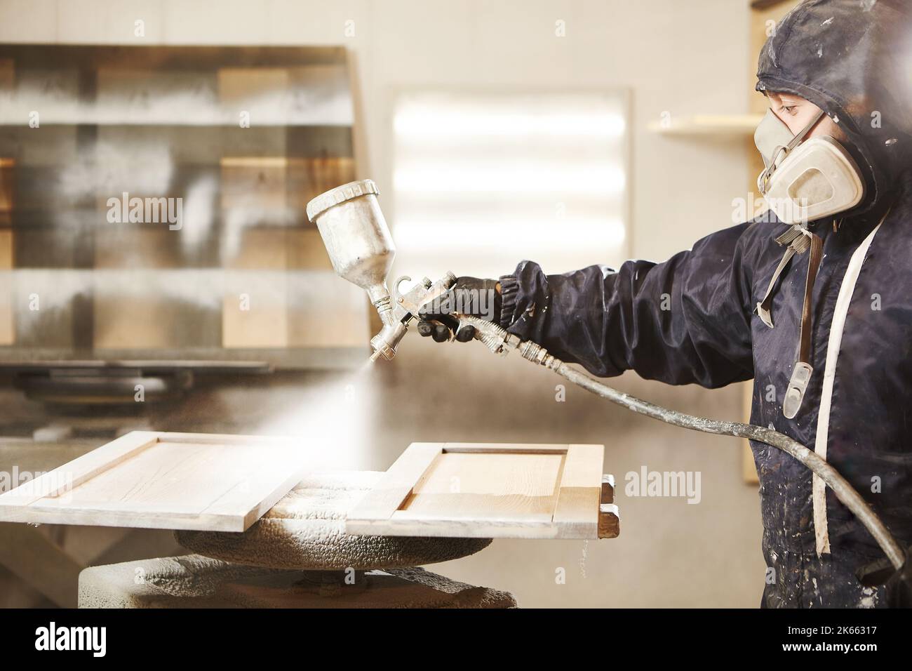 Close-up portrait of worker using spray gun and painting wood Stock ...