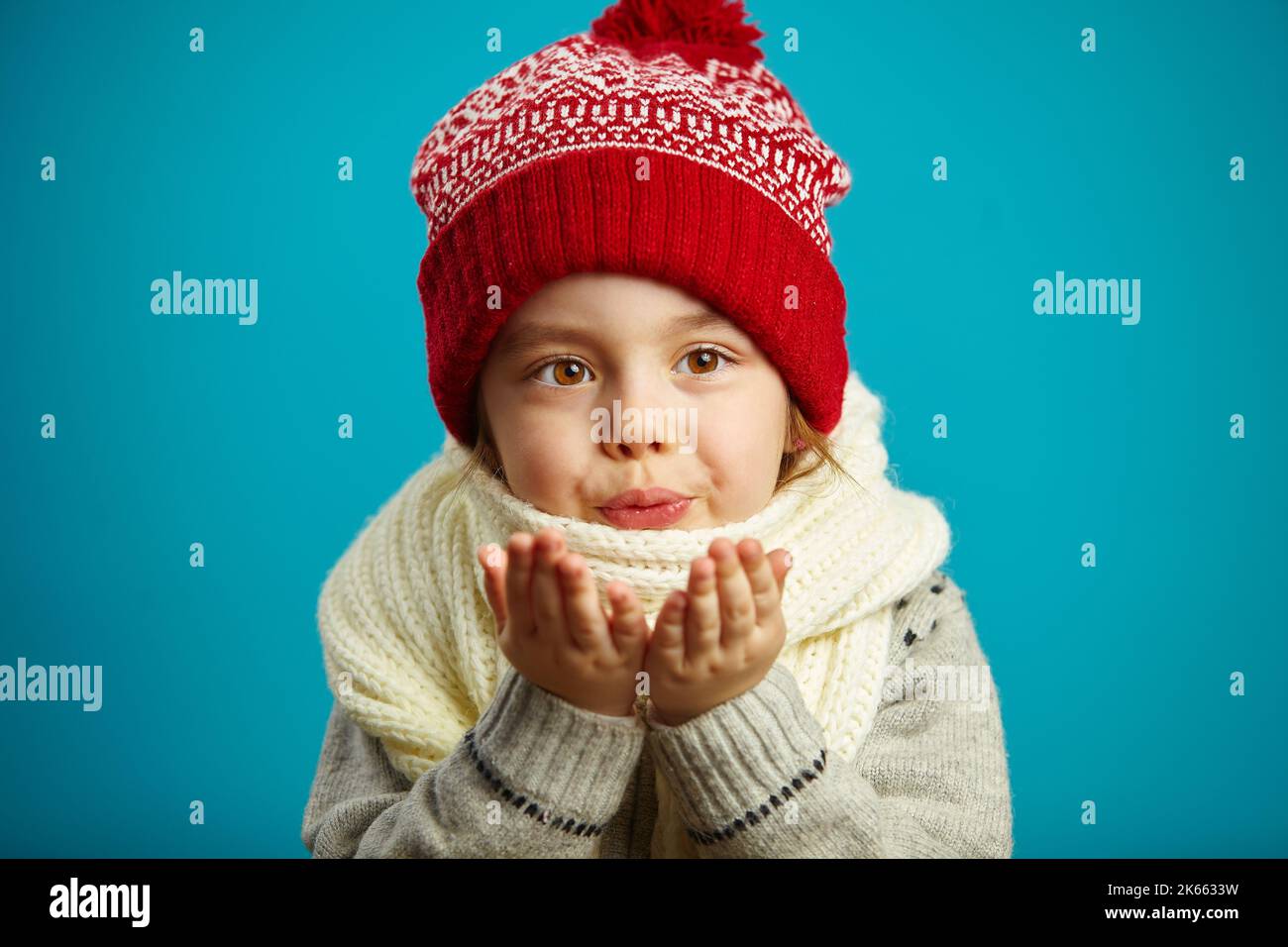 portrait of kid girl in winter red hat, folded her hands together and ...