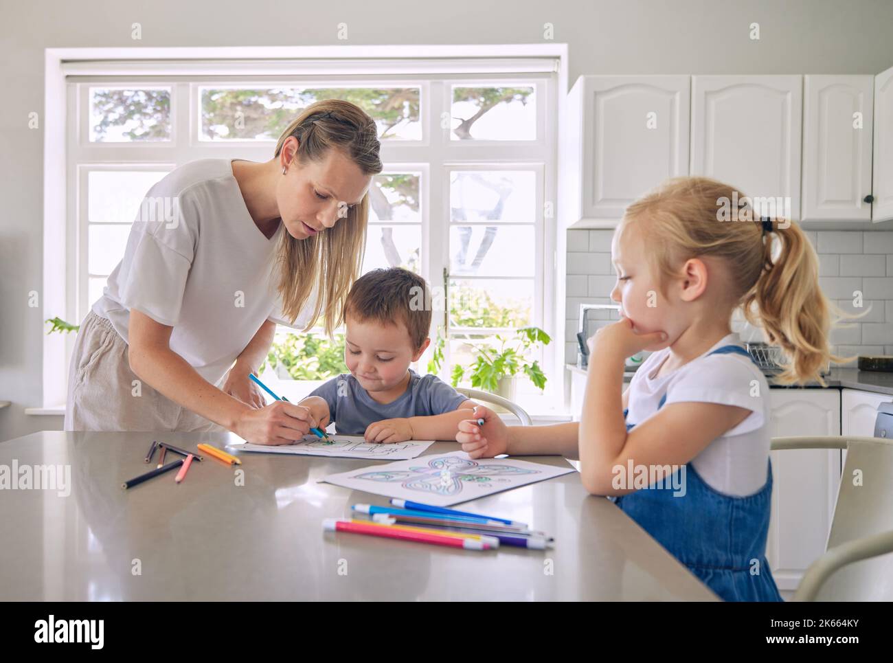 Caucasian mother helping her young little children drawing in a book ...