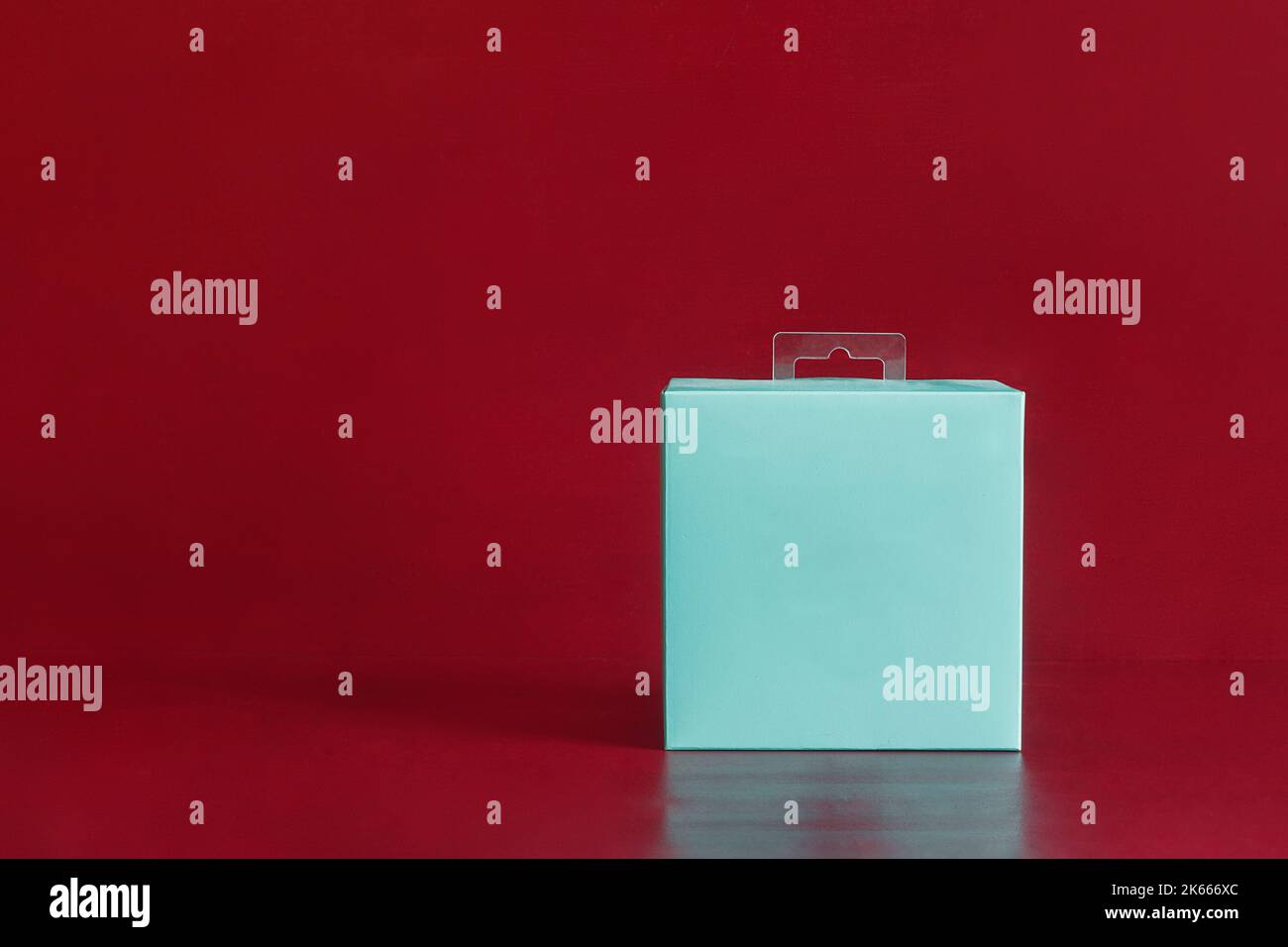 A blank blue square cardboard package box on a colorful red studio ...