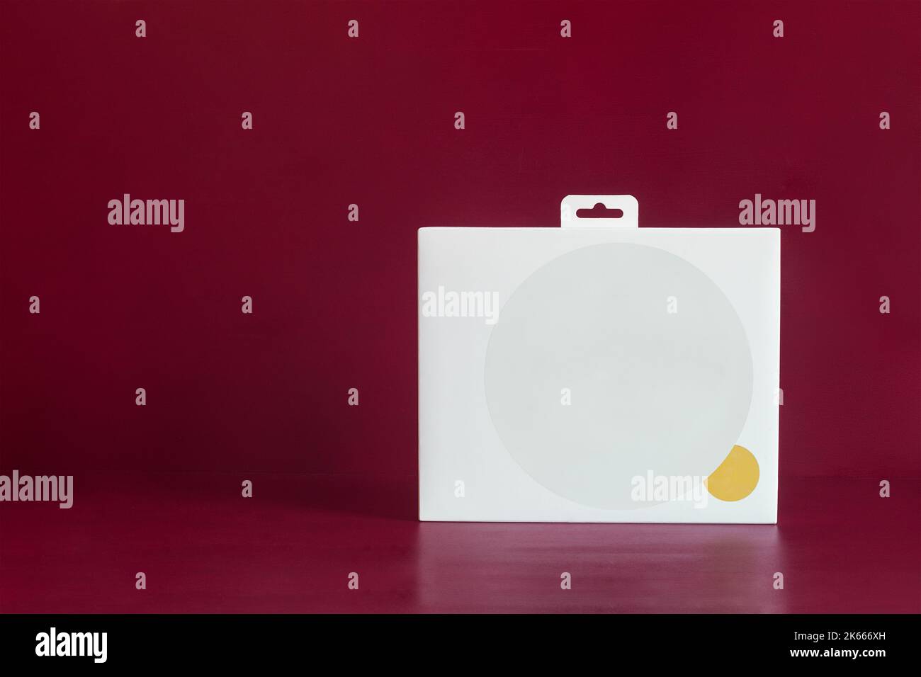 A white cardboard box with a large blank grey circle and a small gold ...