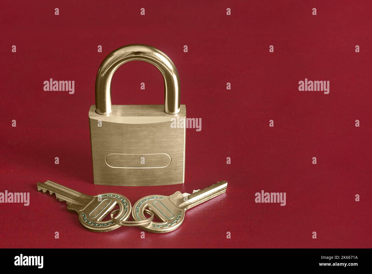 A closed gold padlock on a red studio background along with a pair of ...