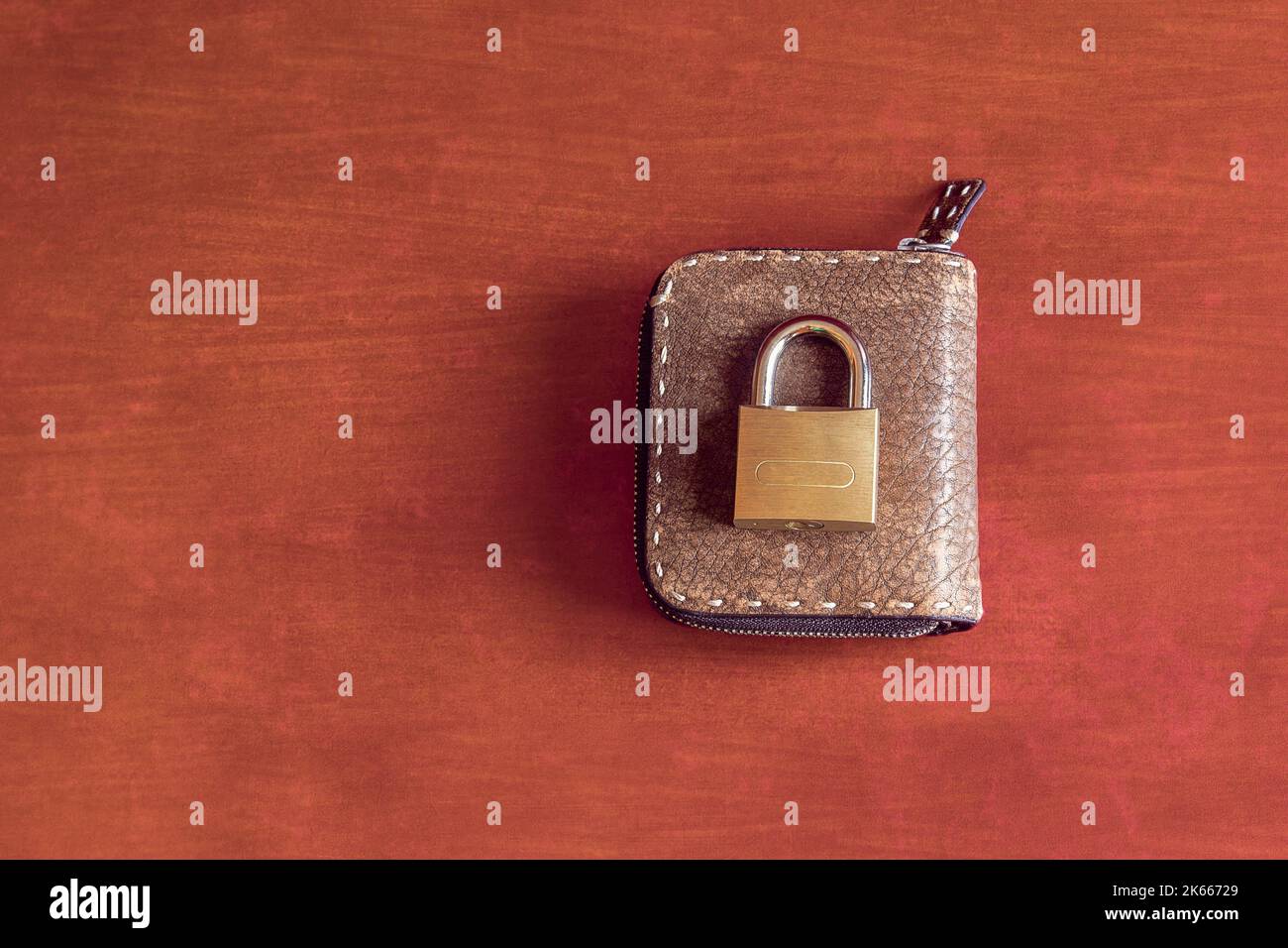A closed padlock on a zippered leather wallet on a colorful studio ...