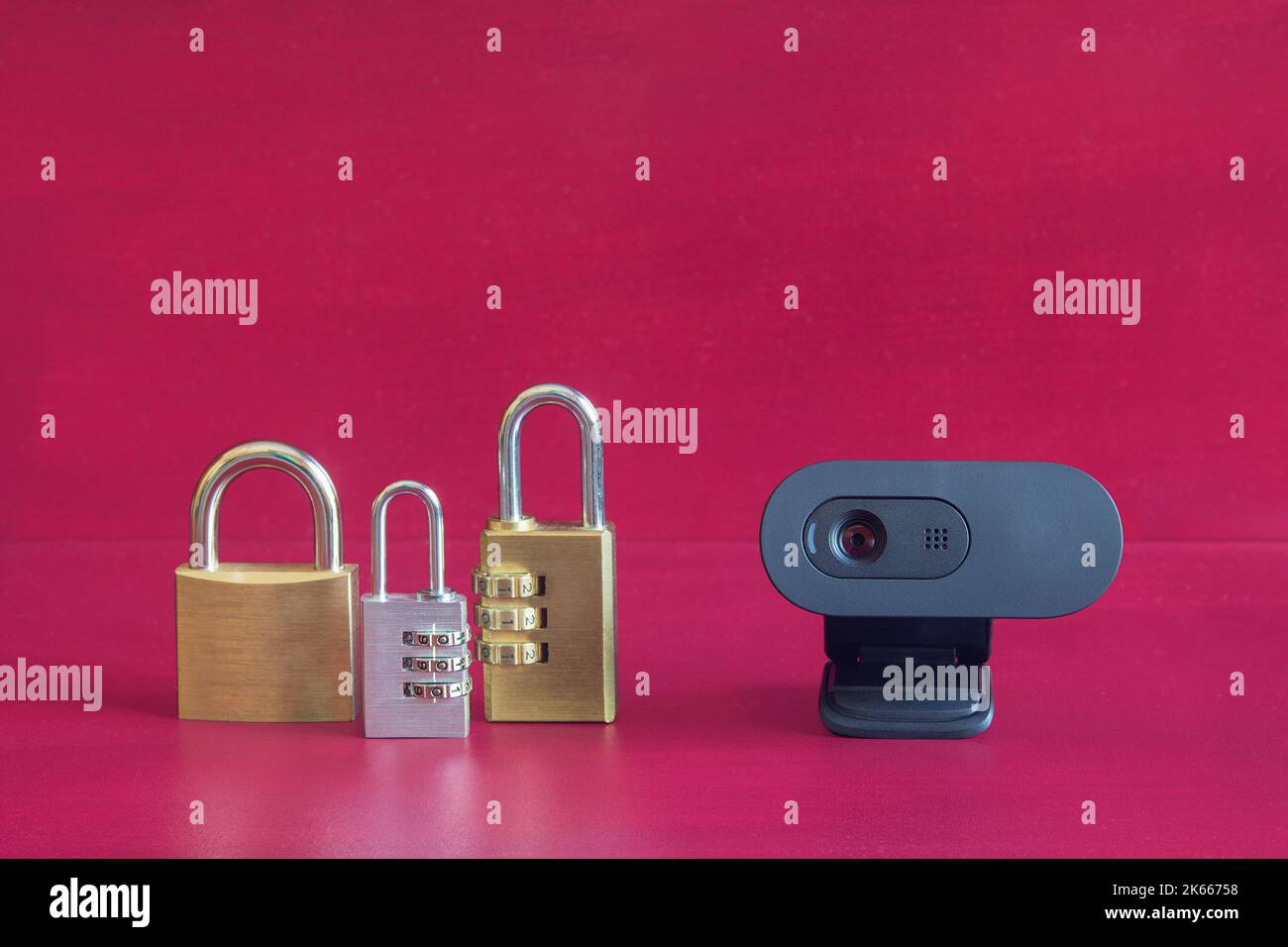 A webcam on its stand and three different locked padlocks on a colorful ...