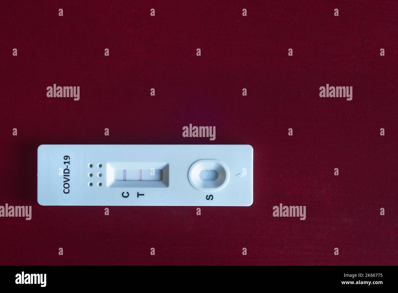 A positive rapid antigen test for Covid-19 on a red wooden textured ...