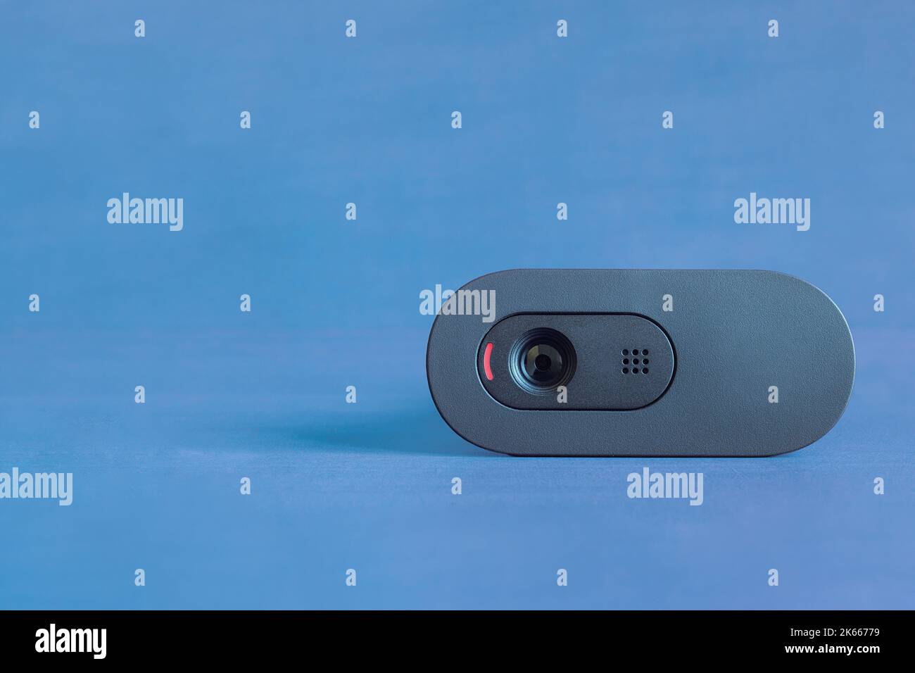 A webcam with the red light on ready to record on a colorful blue ...