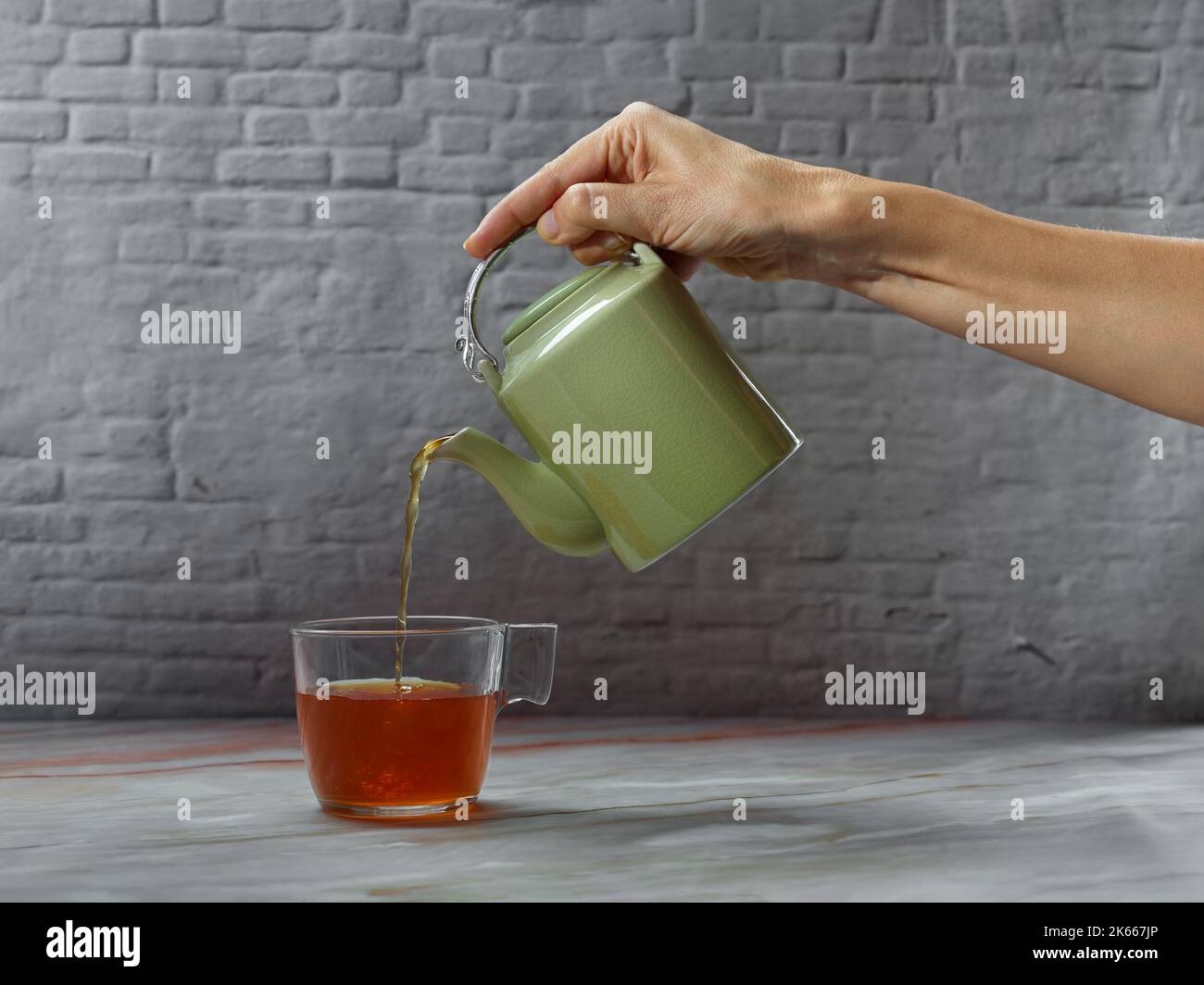 Hand picking up a green teapot, pouring tea into a glass cup Stock ...