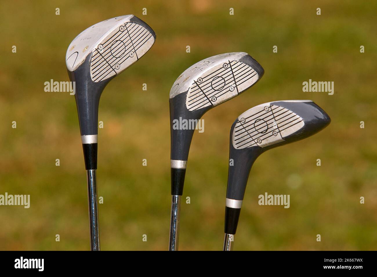 Detail of three golf clubs with a green background Stock Photo - Alamy