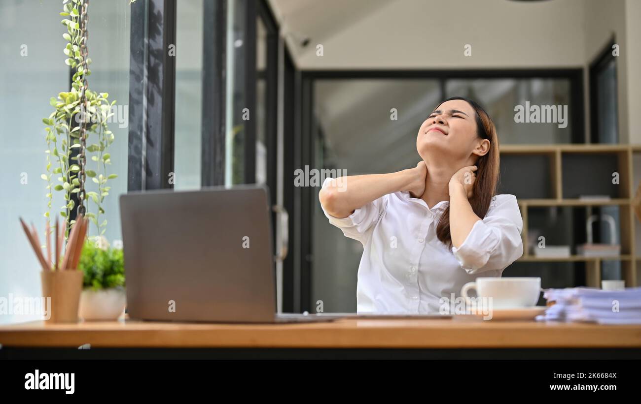 Exhausted young Asian businesswoman or female office worker suffering ...