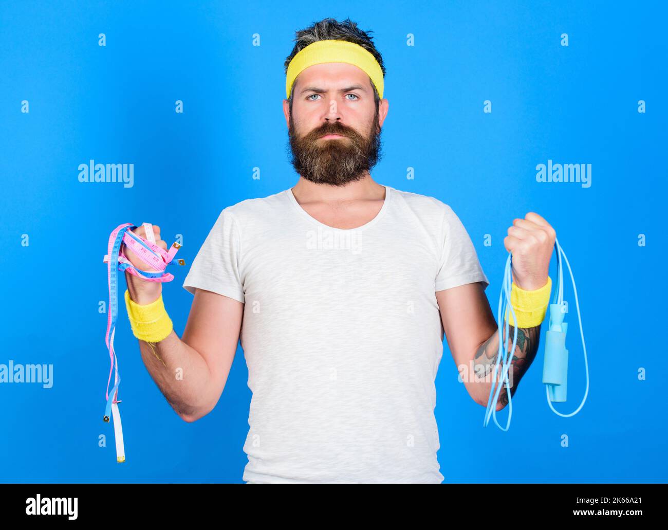 Man bearded athlete hold jump rope and tape measure. Athlete guide stay ...