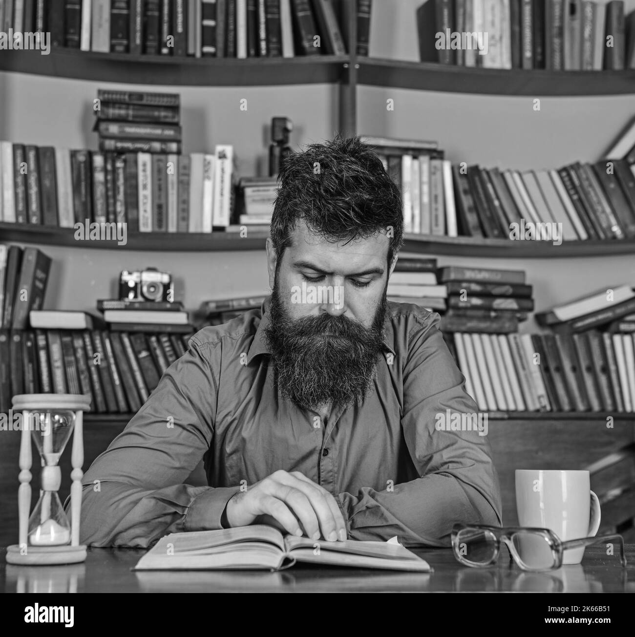 Man on concentrated face reading book, studying, bookshelves on ...