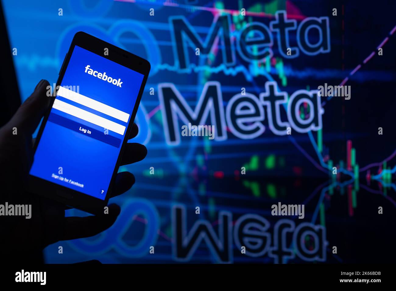 A smartphone with Facebook login screen and Meta logo in the background ...