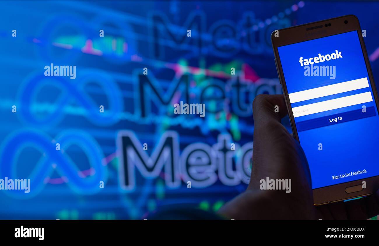 A smartphone with Facebook login screen and Meta logo in the background ...