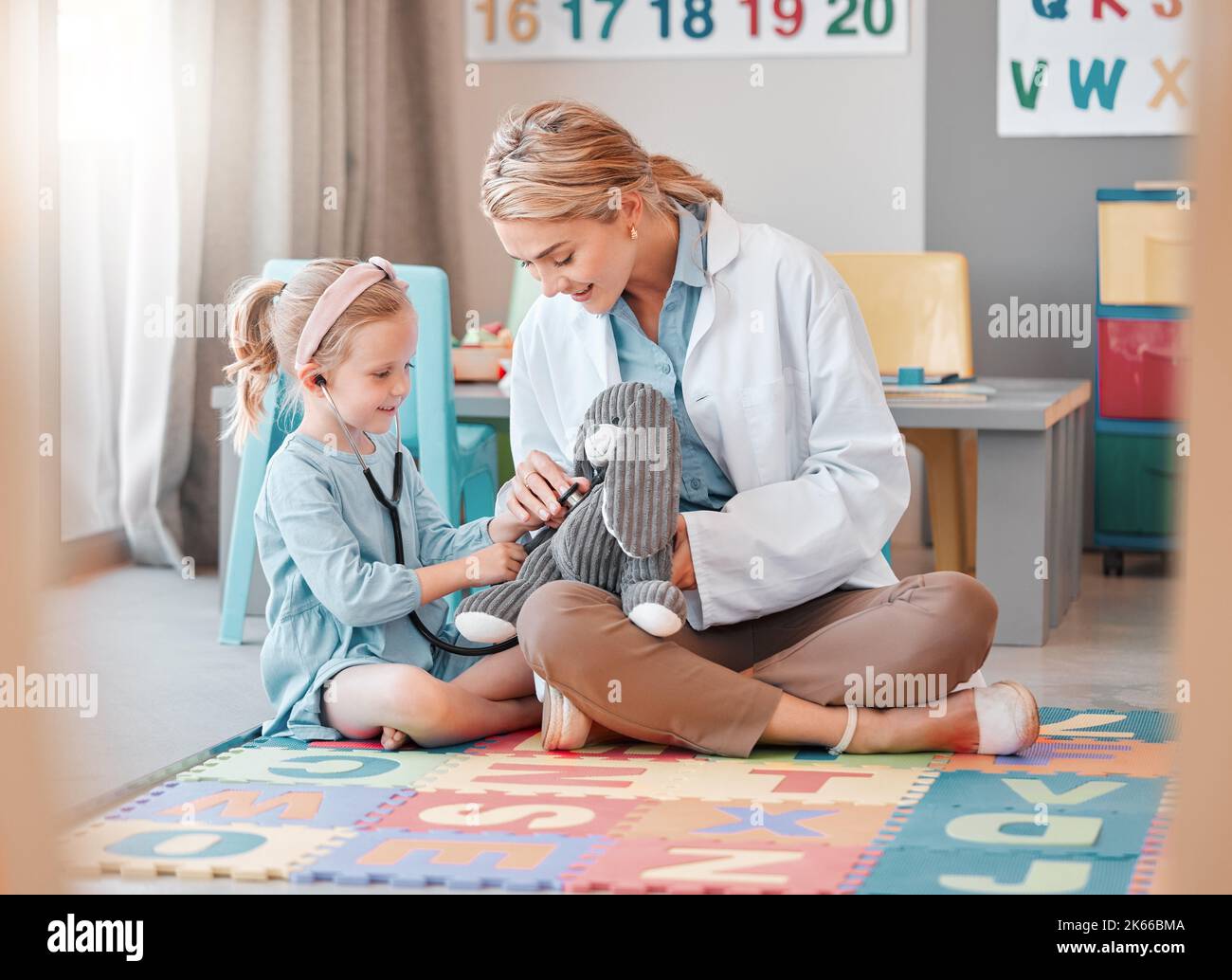 Young caucasian paediatrician helping a little girl listen to the ...