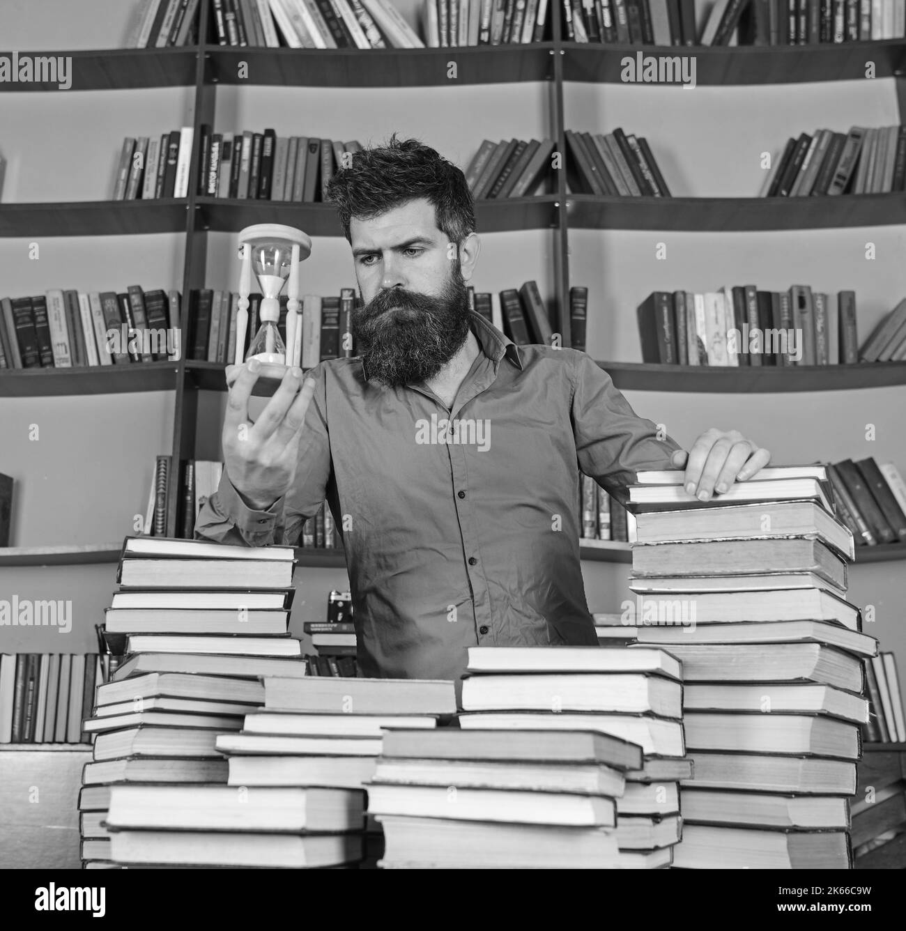 Librarian concept. Teacher, scientist with beard stands at table with ...