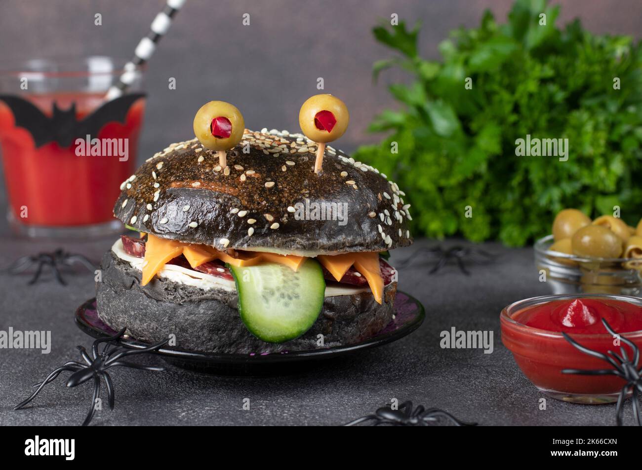 Monster sandwich with black bun, sausage, cheese, cucumber and olive ...