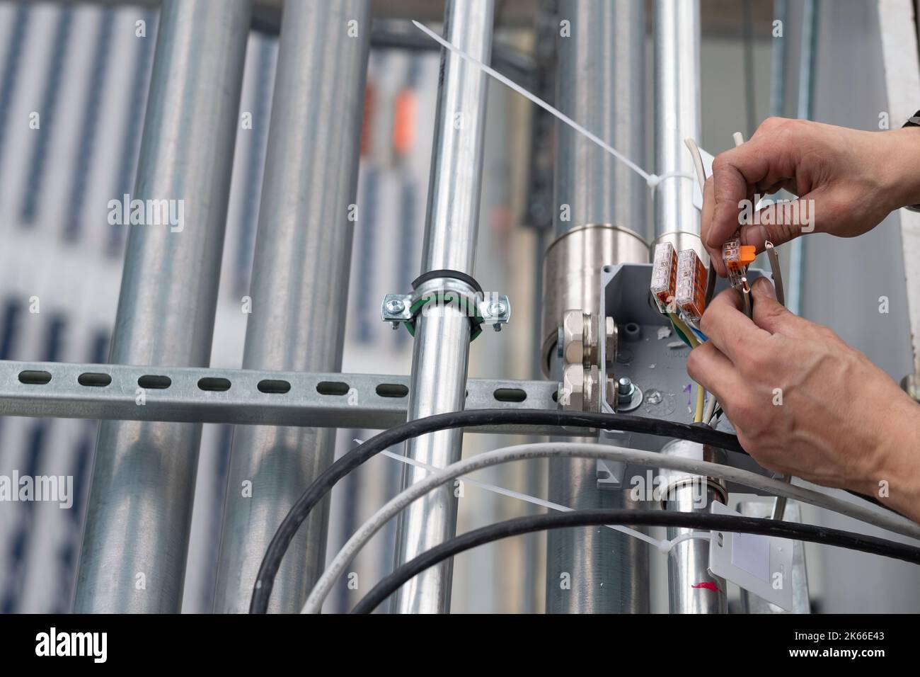 Electrical engineer connects wires to terminals in a junction box ...